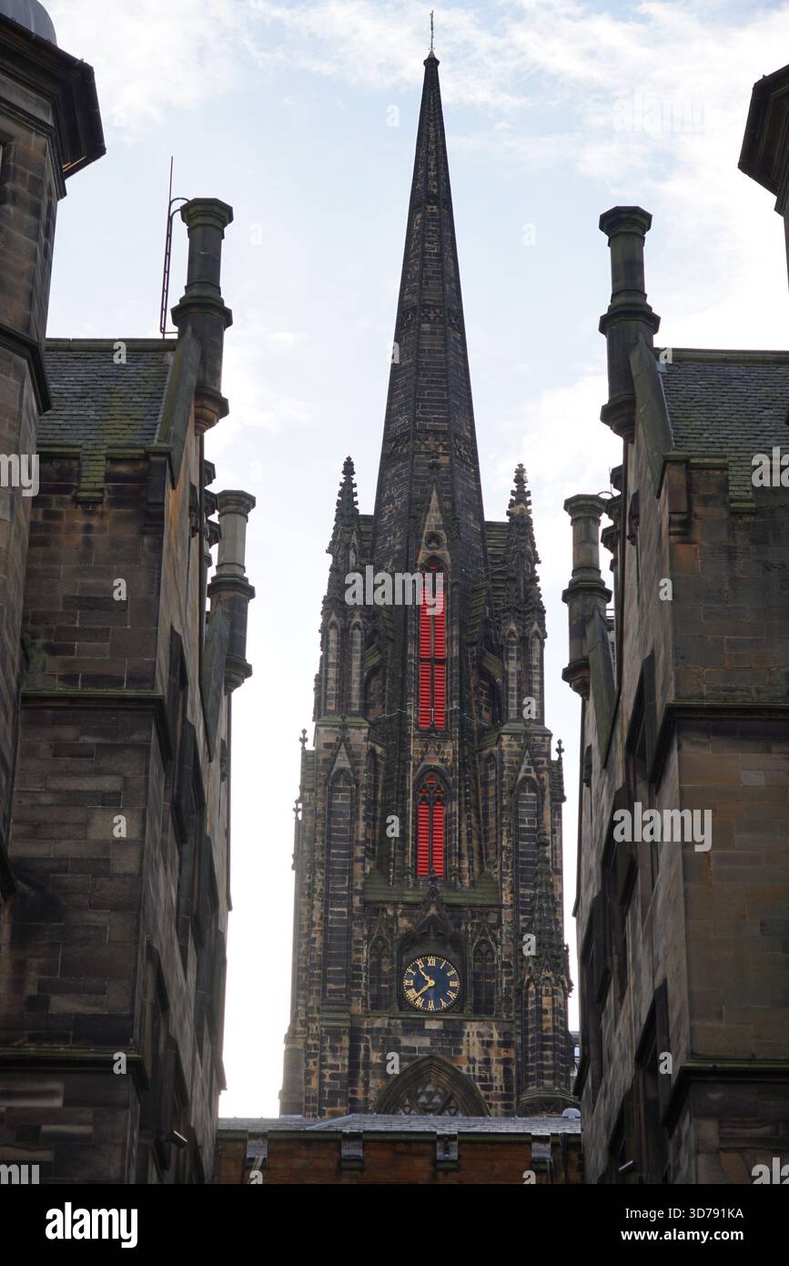 Gothic church tower with a tall spire and red window accents rising ...