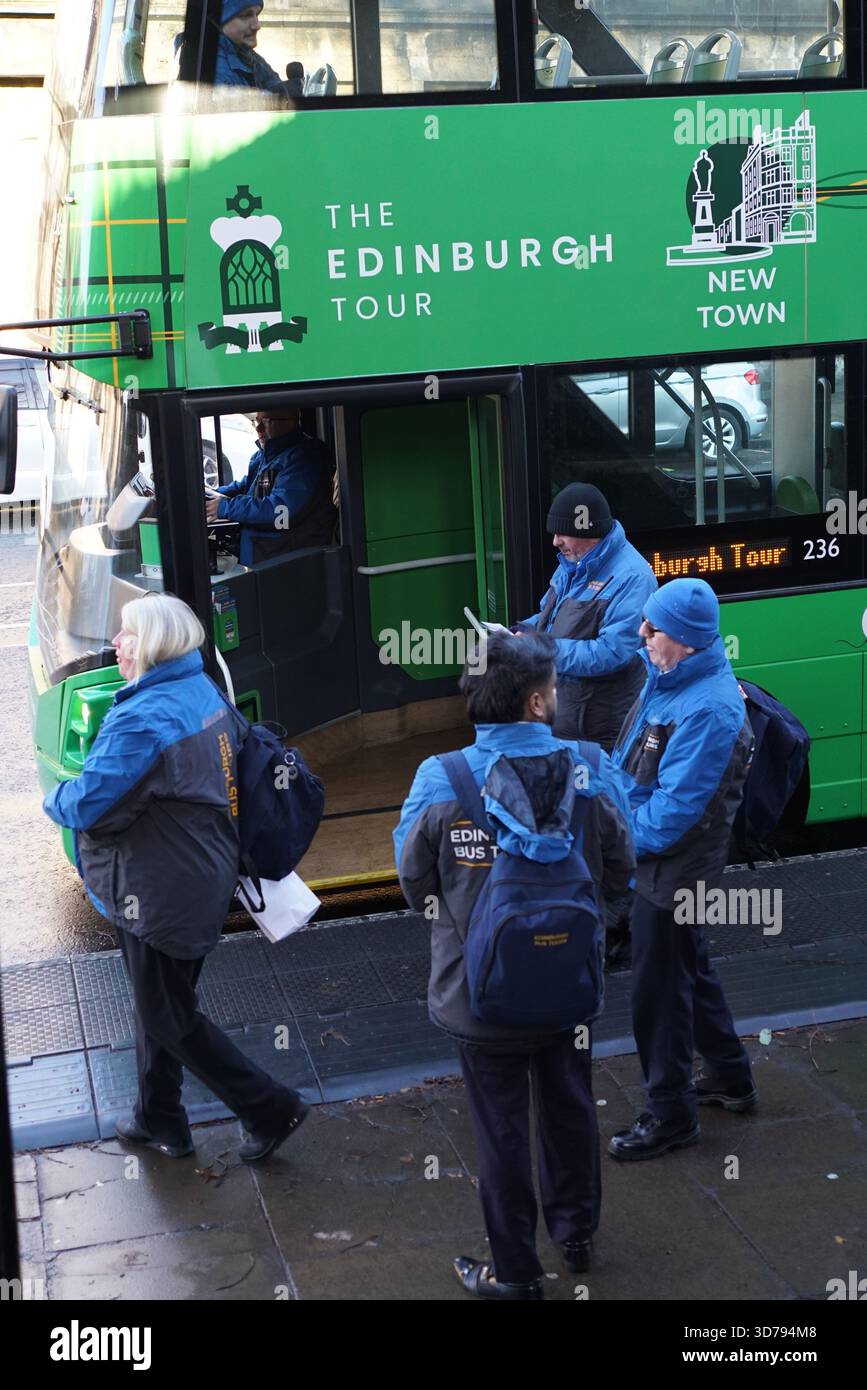 Tour bus staff and passengers preparing to board a green Edinburgh ...
