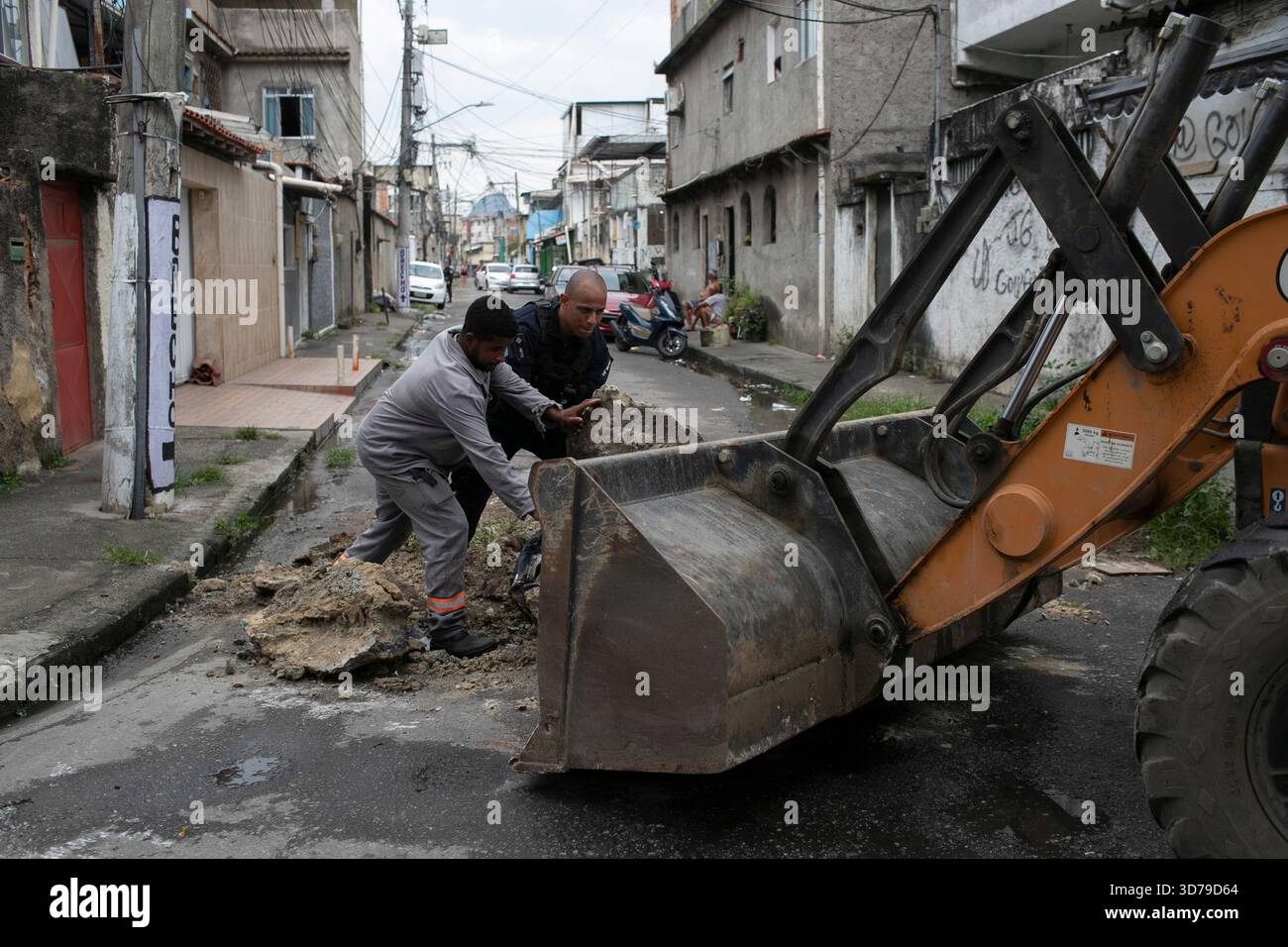 A police officer and a worker clear a blocked street during a ...