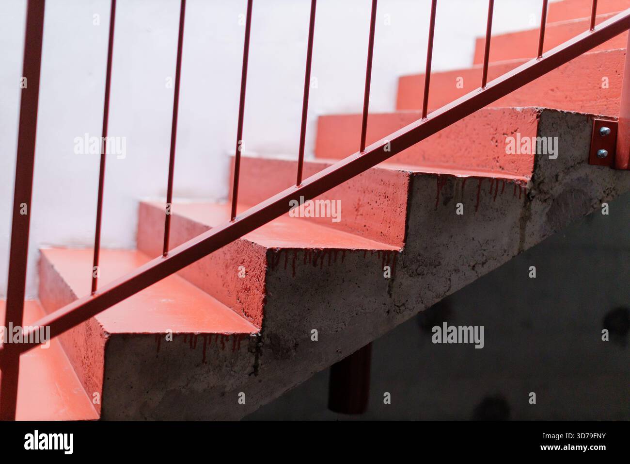 Stairs with bright red railing and textured concrete steps in a modern ...
