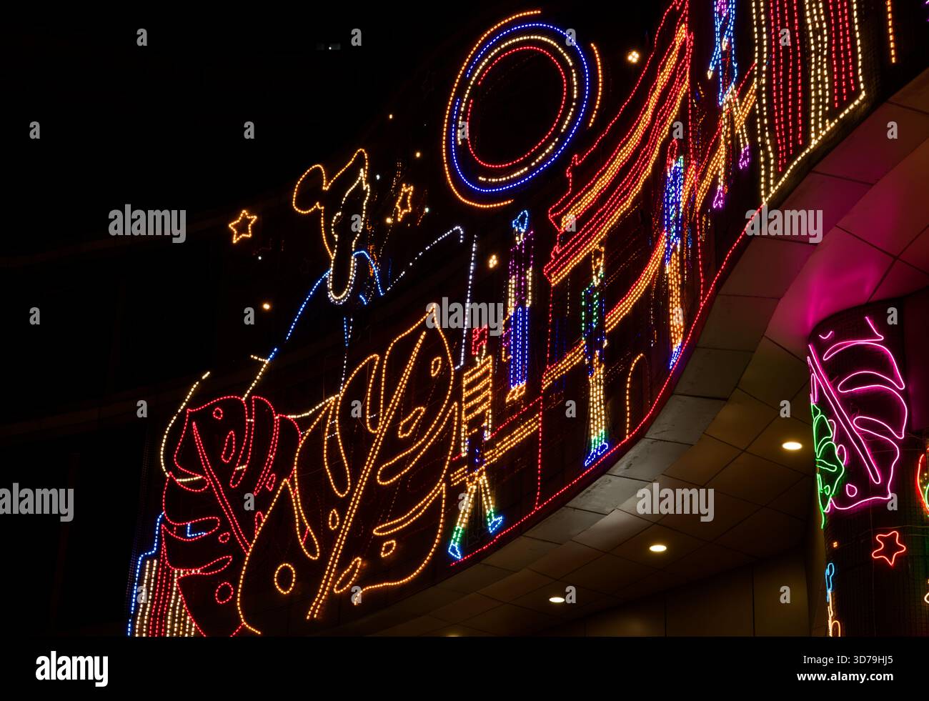 light mural outside a Beijing mall glows at night with cartoon skyline ...