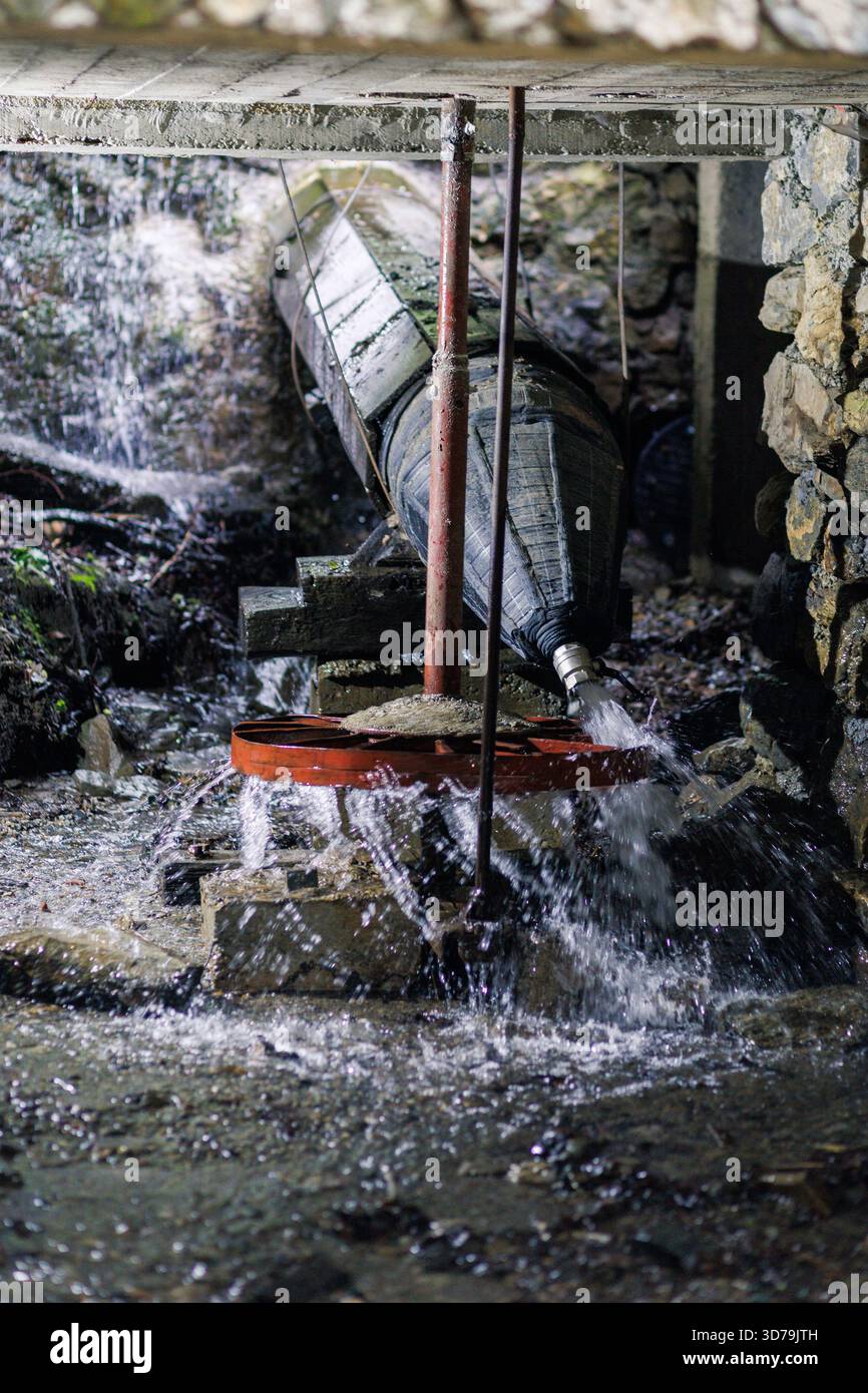 Watermill mechanism operating amidst flowing water in a rustic setting ...