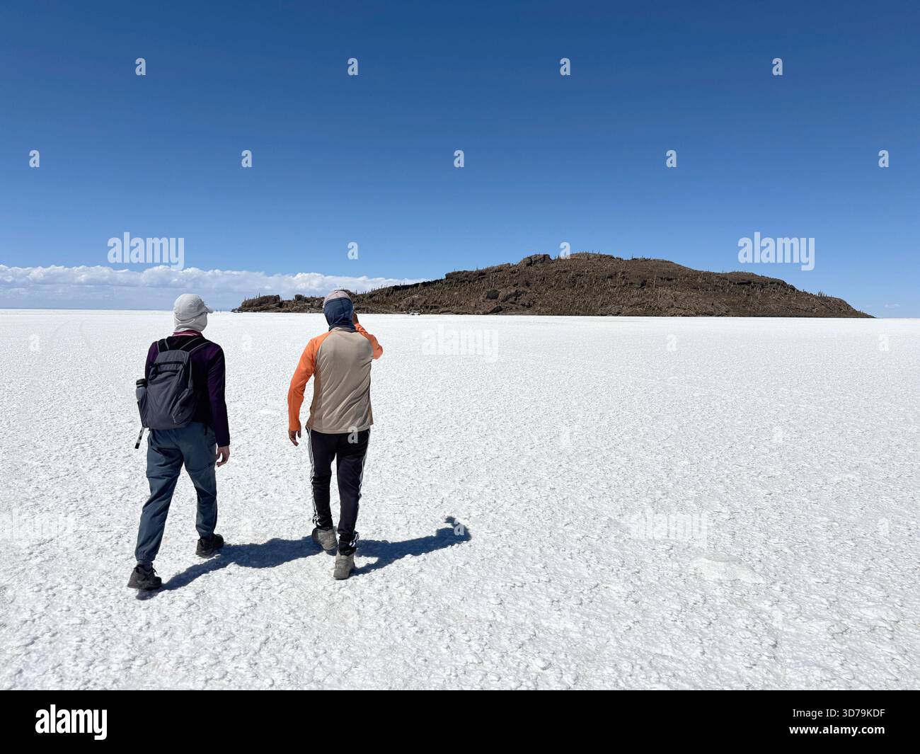 Two people walking across the intense white expanse of Uyuni Salt Flats ...