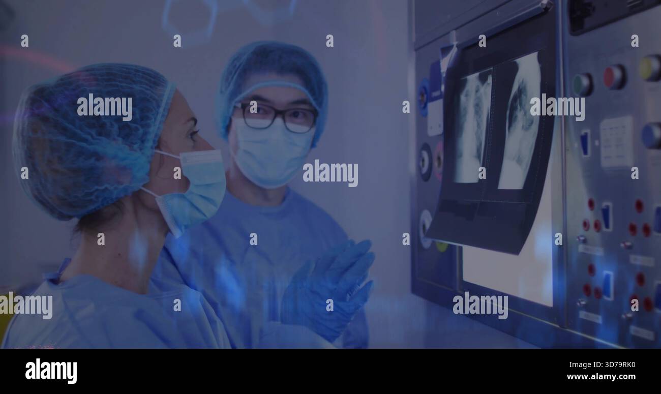 Examining two doctors wearing surgical gear studying chest X-rays in x ...