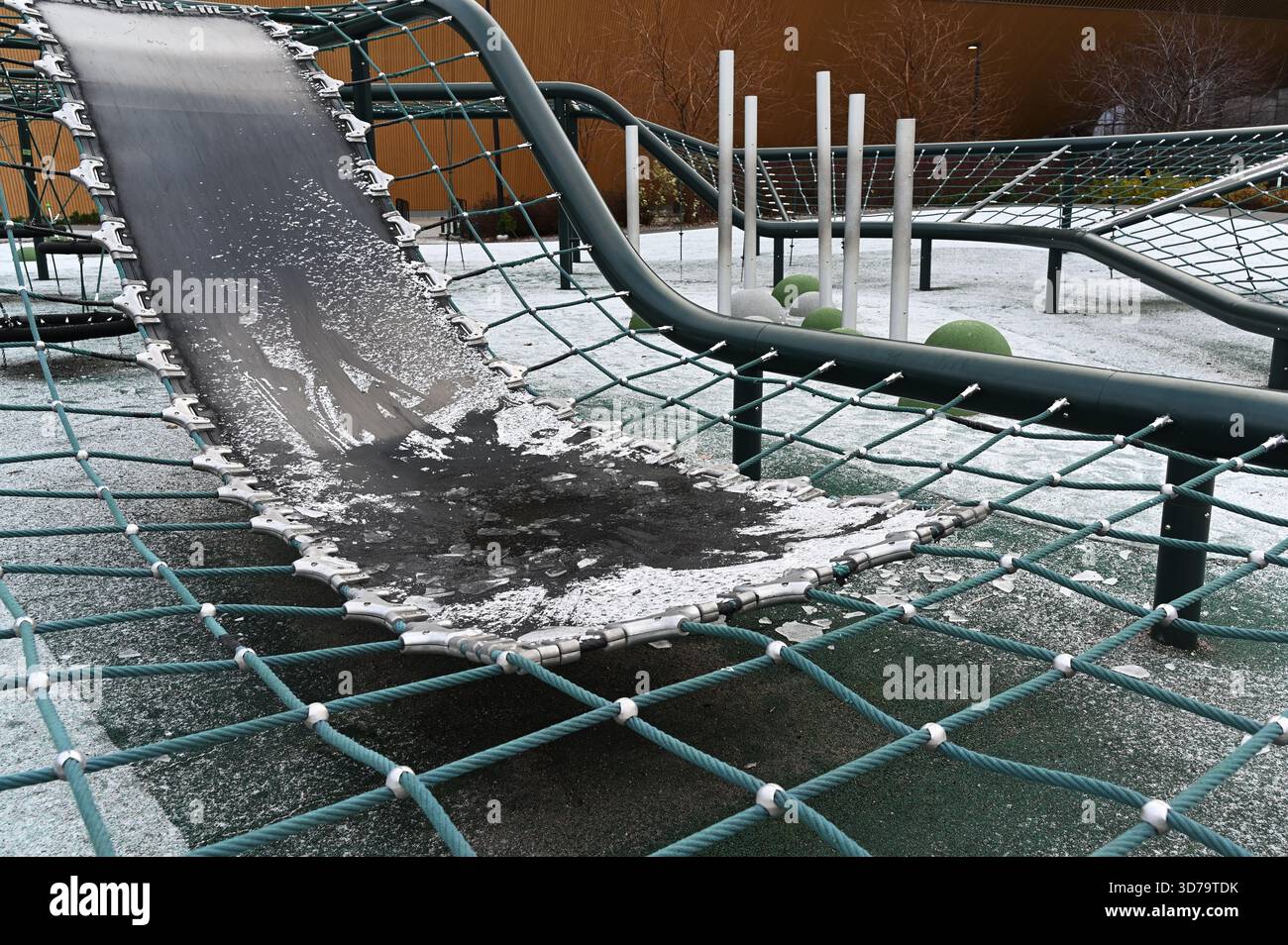 A winter scene of an outdoor playground featuring a large rope climbing ...