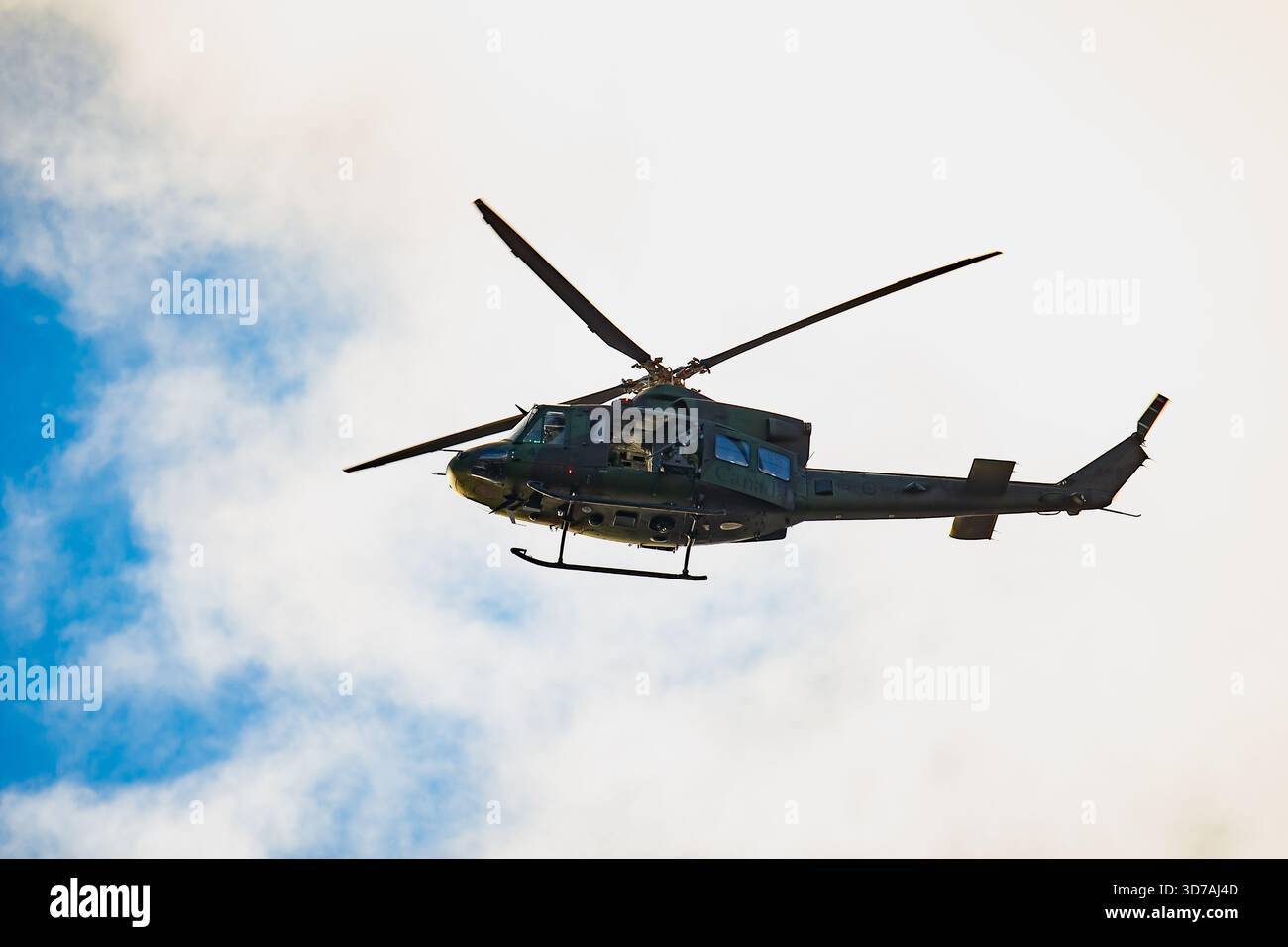 Military helicopter in flight with visible landing skids, cockpit ...