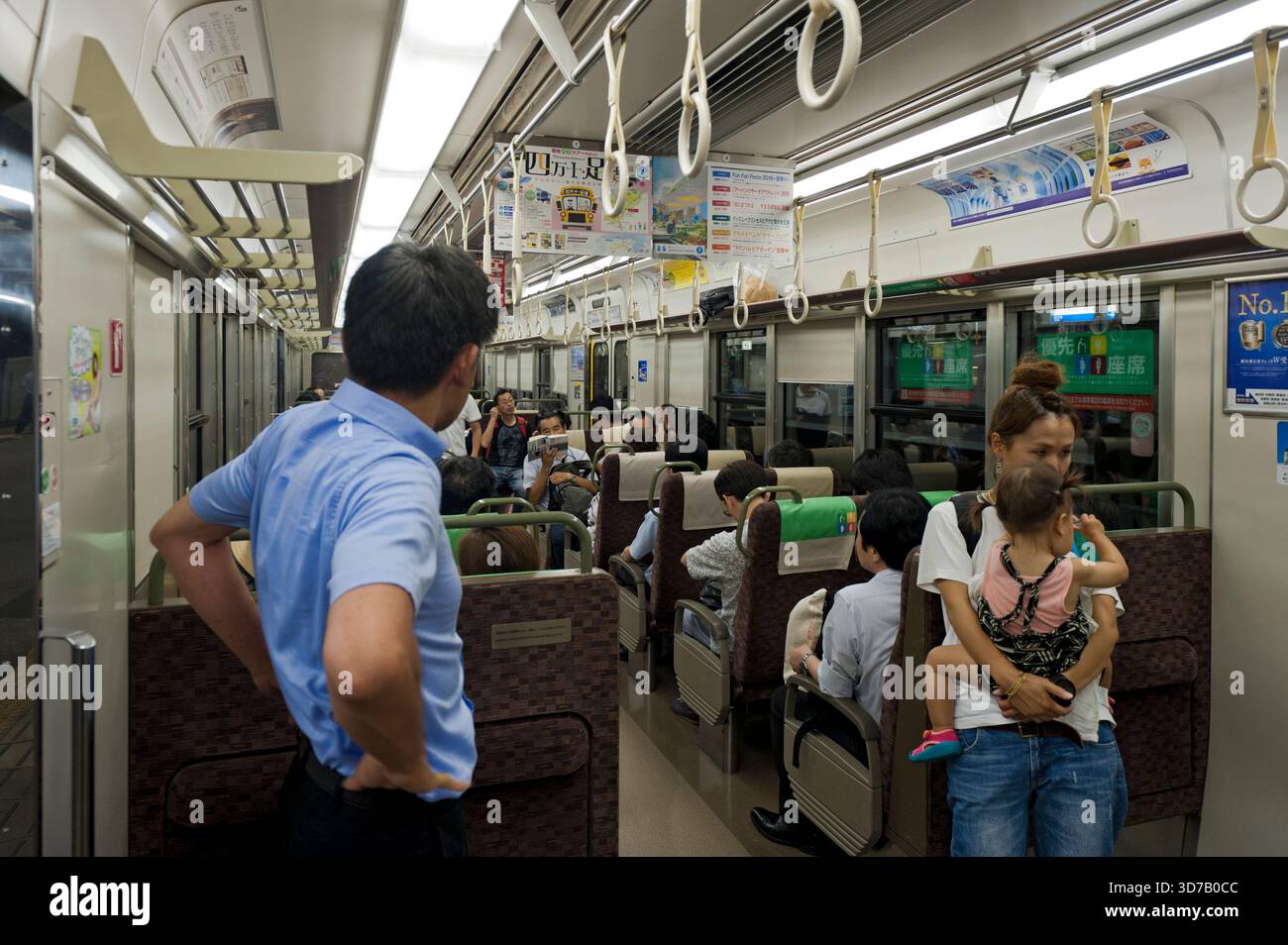 Passengers aboard a Japanese local train inside a carriage of a JR ...
