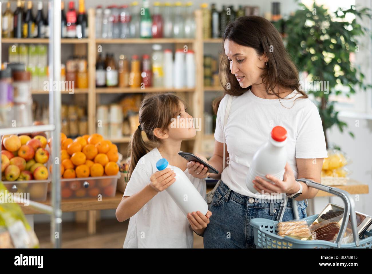 Girl with mother customers at shop scans QR code on milk package using ...