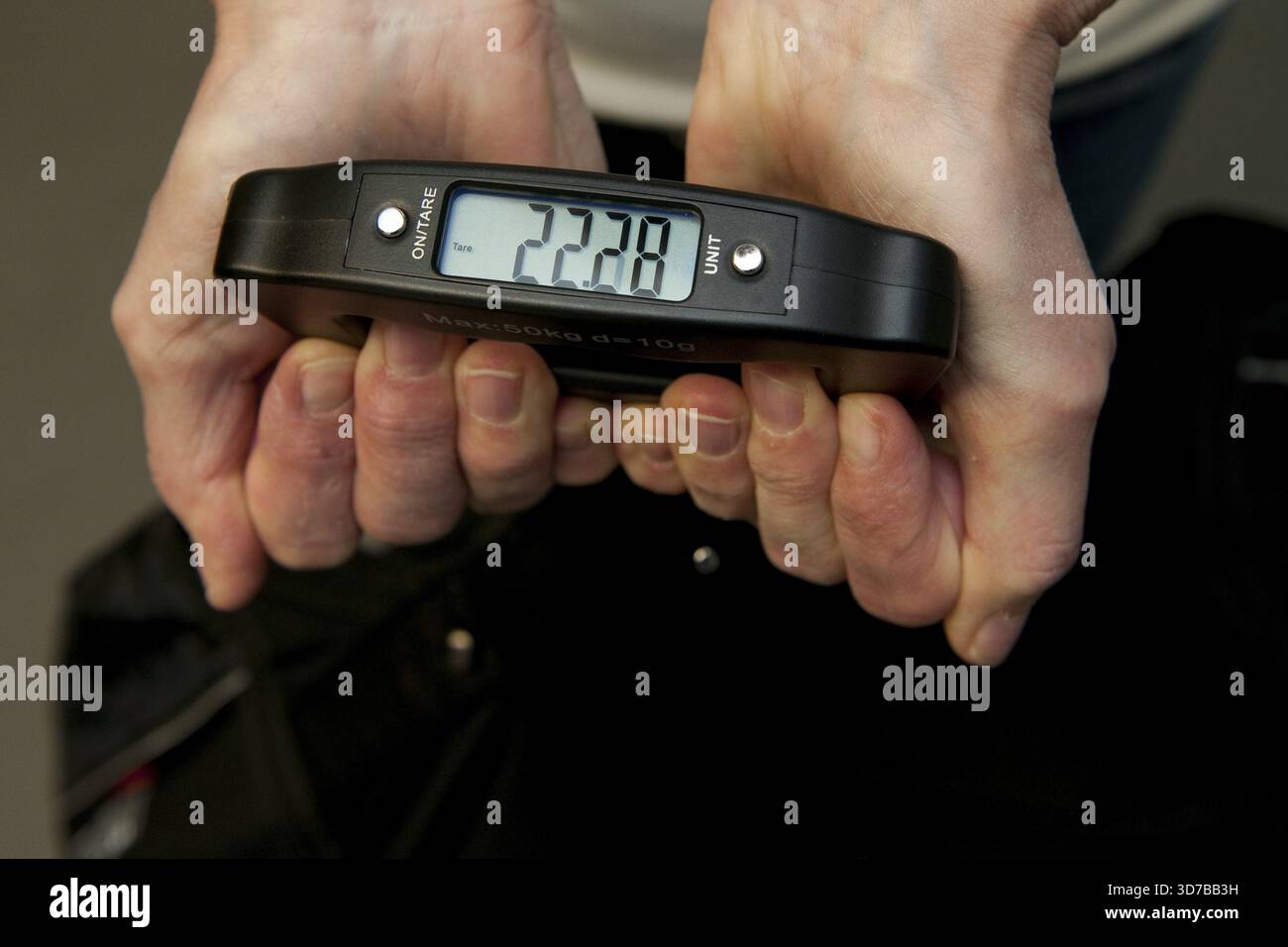 Woman holding hand scale for weight of suitcase travel bag flight ...