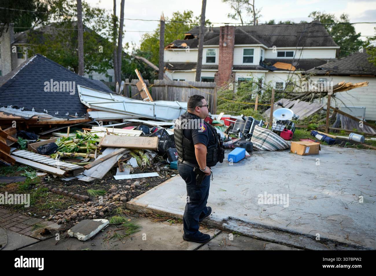 A law enforcement officer surveys damage as clean up of storm damage ...