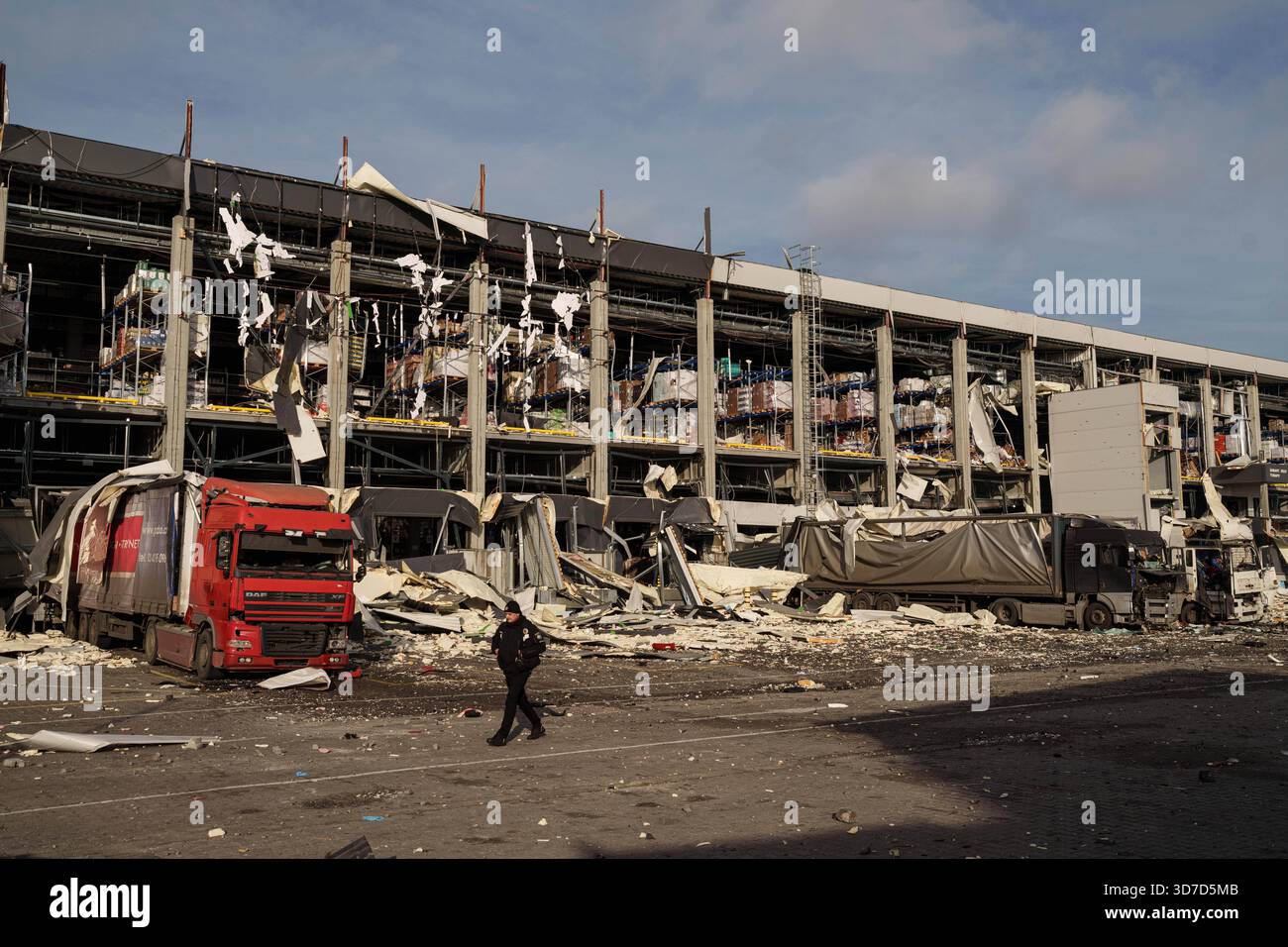A police officer walks in front of a Novus logistics center damaged ...