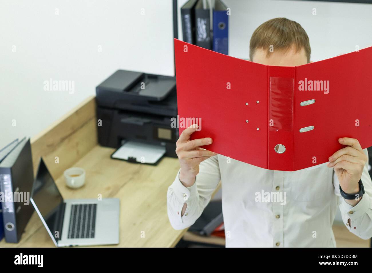 Employee concealing identity with open red binder in professional ...
