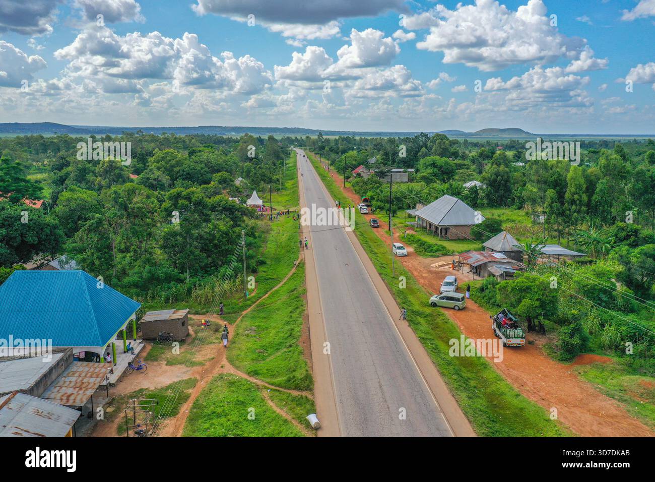 Aerial view of a long, straight asphalt road cutting through a lush ...