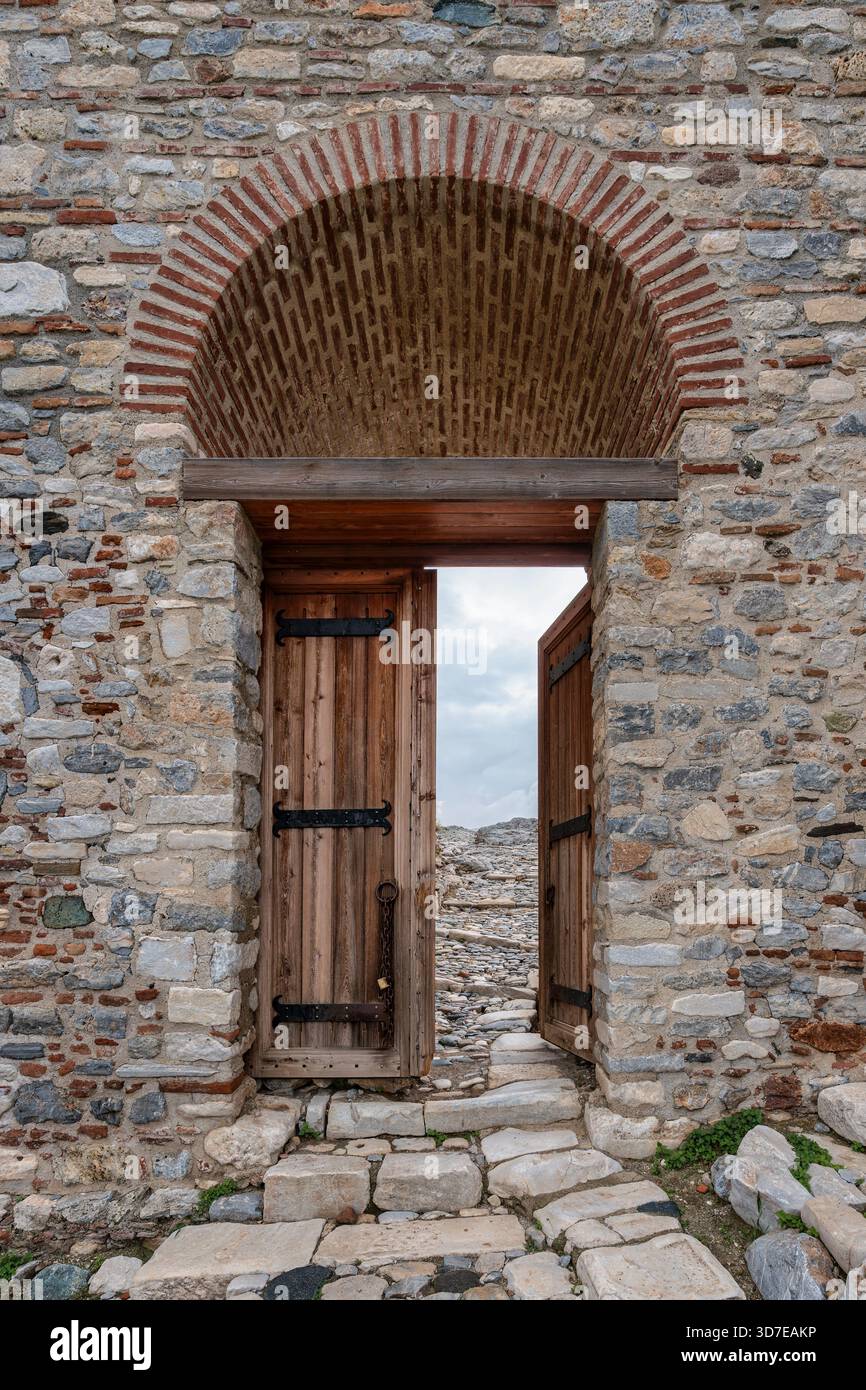 Historic stone and brick wall with an arched entrance. An old wooden ...