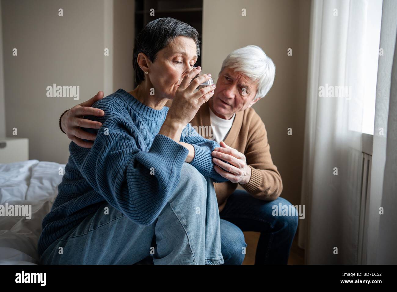 Upset grieving woman drinking water with trembling hand while elderly ...