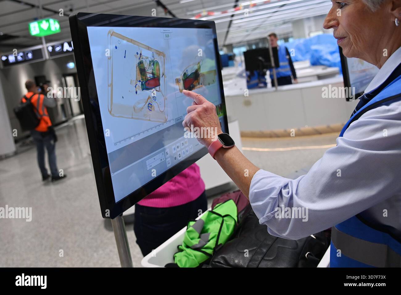 Aviation security screening personnel shows a monitor displaying an X ...