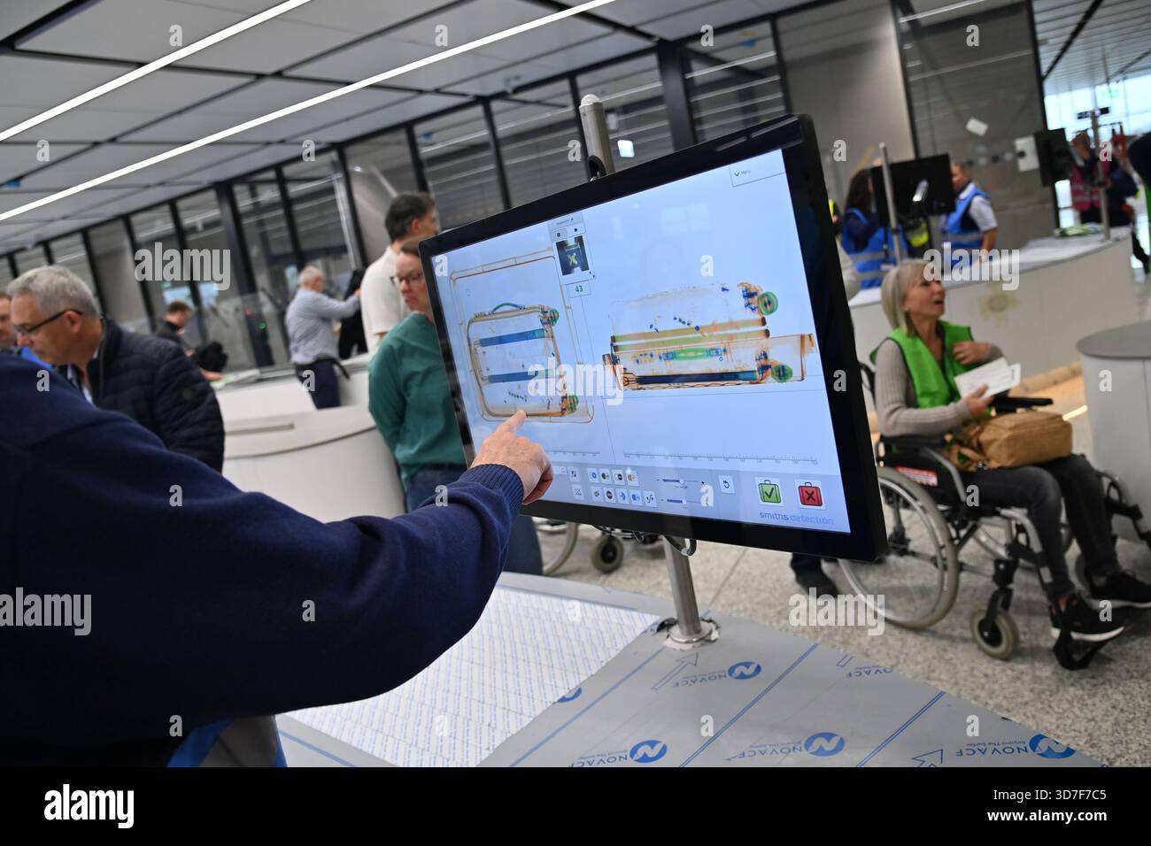 Aviation security screening personnel shows a monitor displaying an X ...