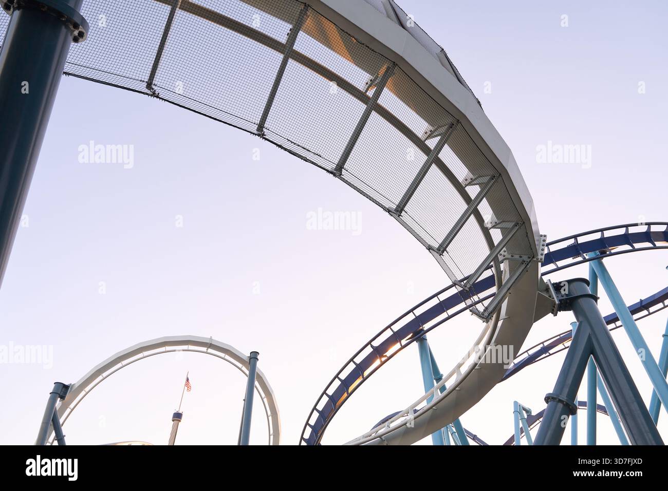 A sweeping coaster curve with safety netting arcs across the sky. Steel ...