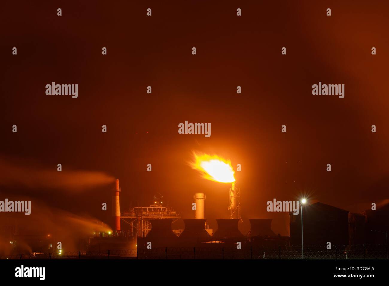 An industrial flare stack burns off excess gas with a large, bright ...