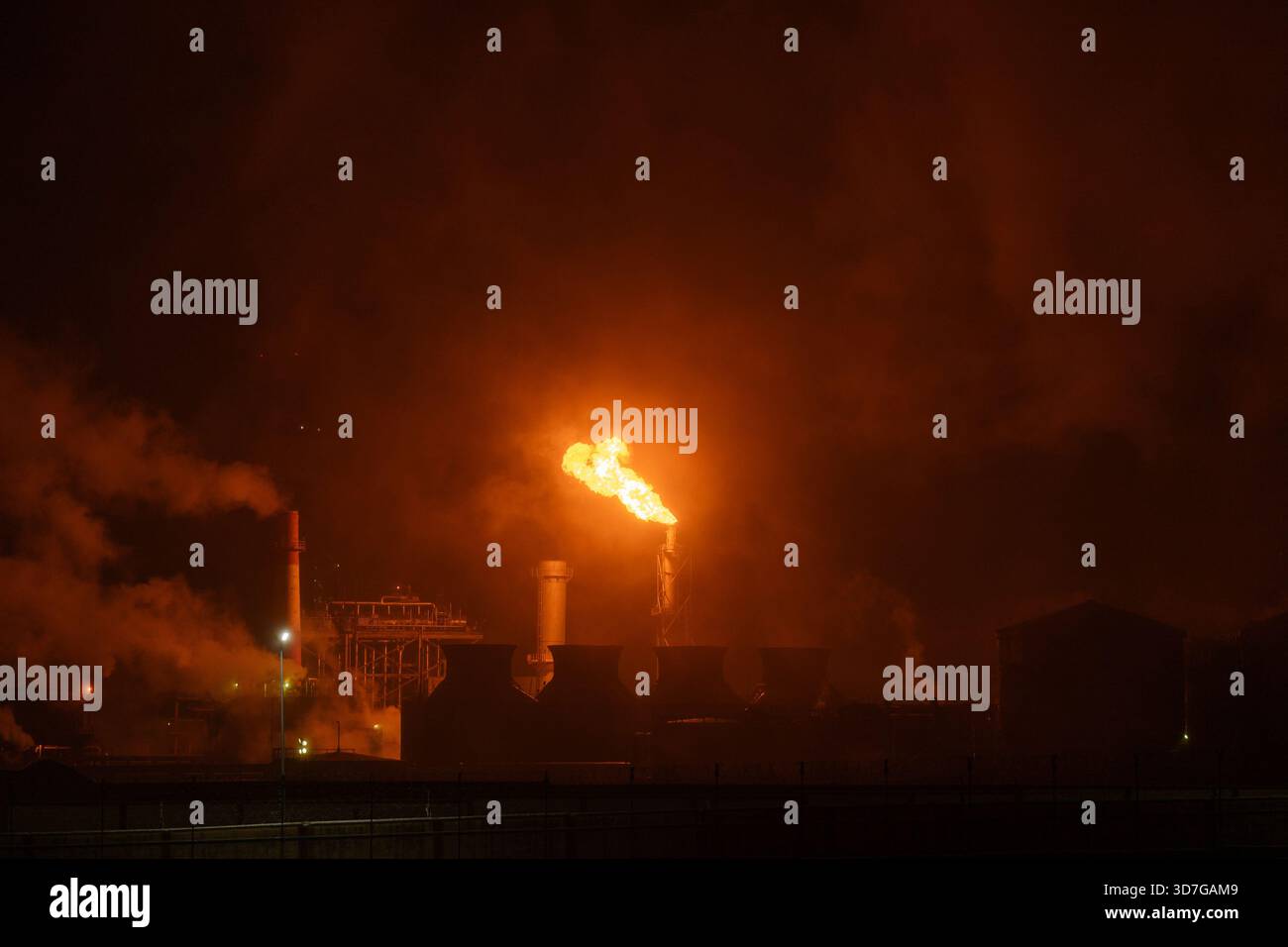 An industrial flare stack burns off excess gas with a large, bright ...