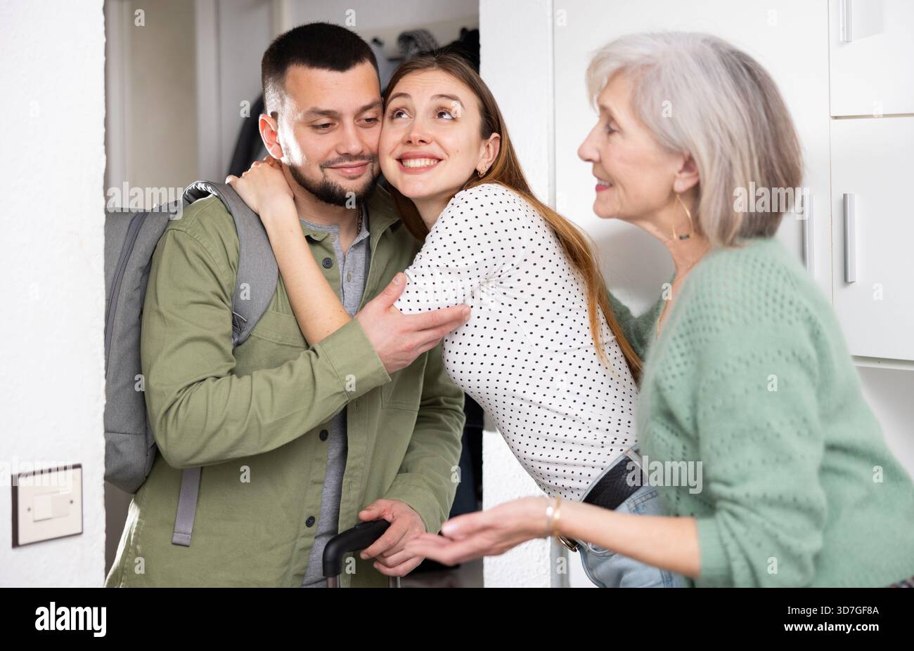 Woman and her mother welcoming man at home Stock Photo - Alamy