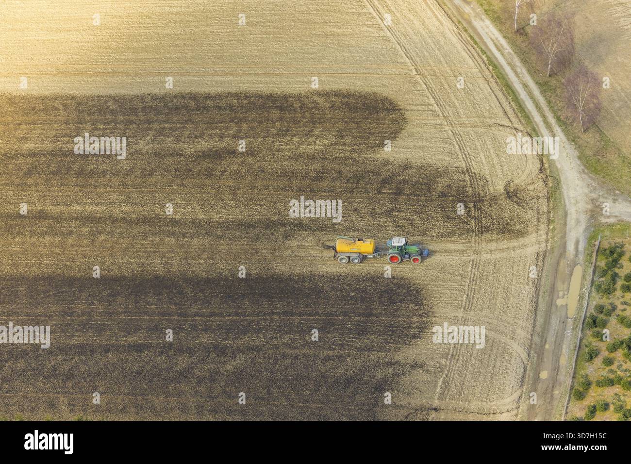 Aerial view of the spraying of manure as fertilizer with tractor and ...