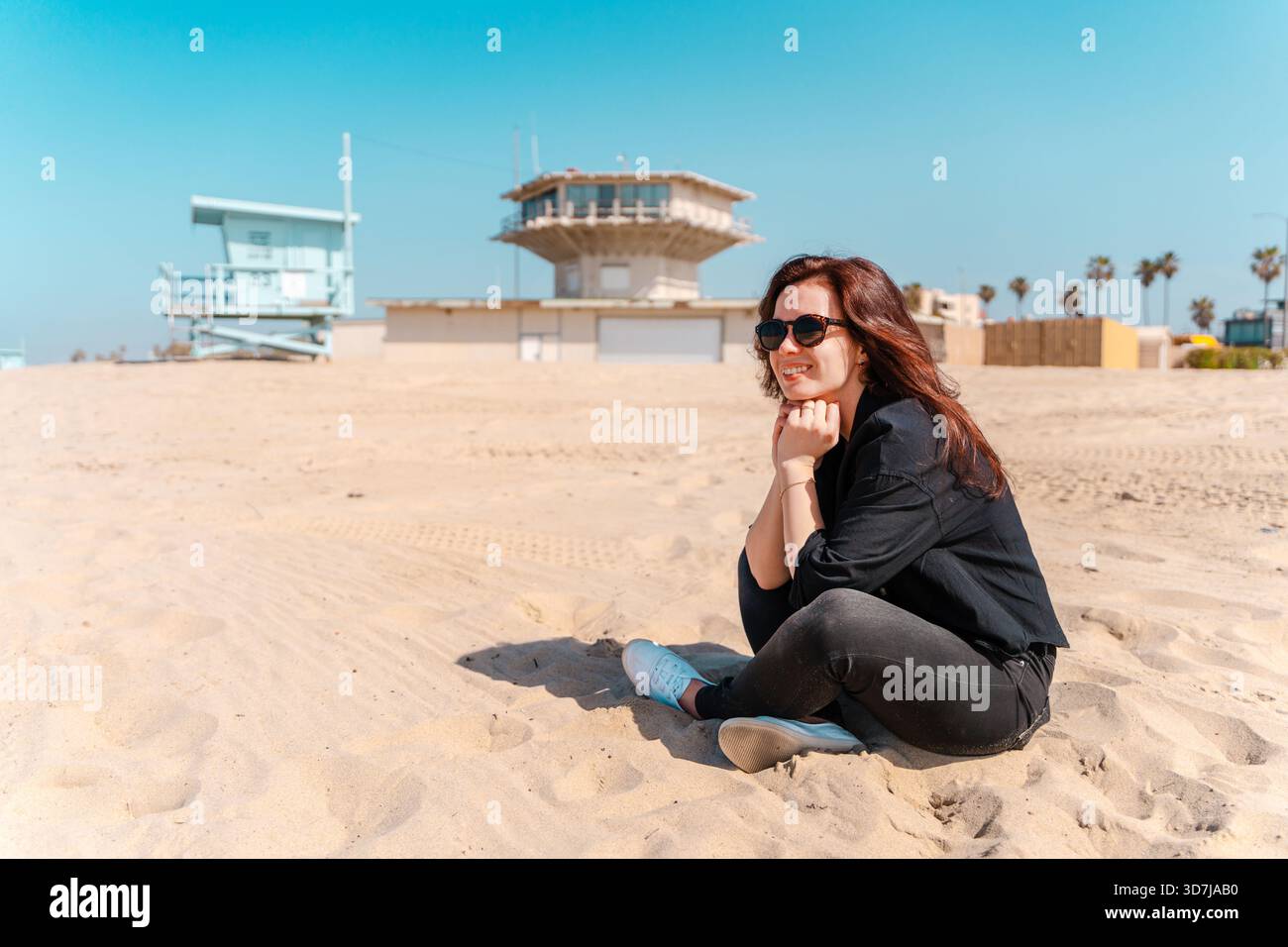 Beautiful young woman with long hair in a black shirt poses on a light ...