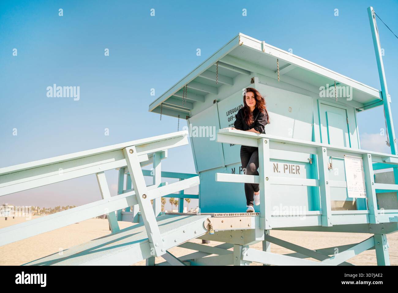 Beautiful young woman with long hair in a black shirt poses on a light ...