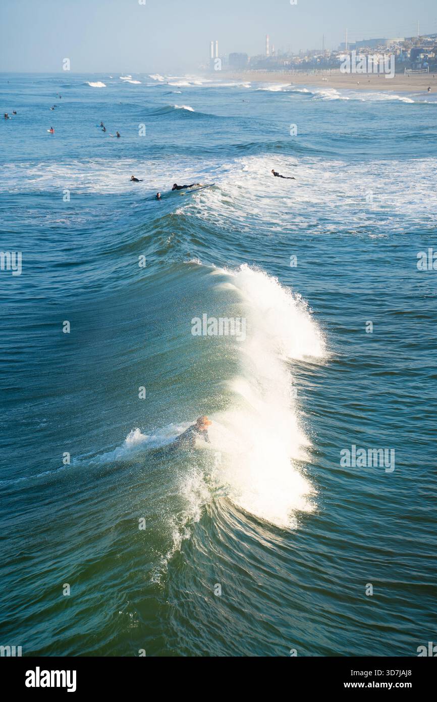 Surfers catch a wave in the Pacific ocean on the coast. Los Angeles ...