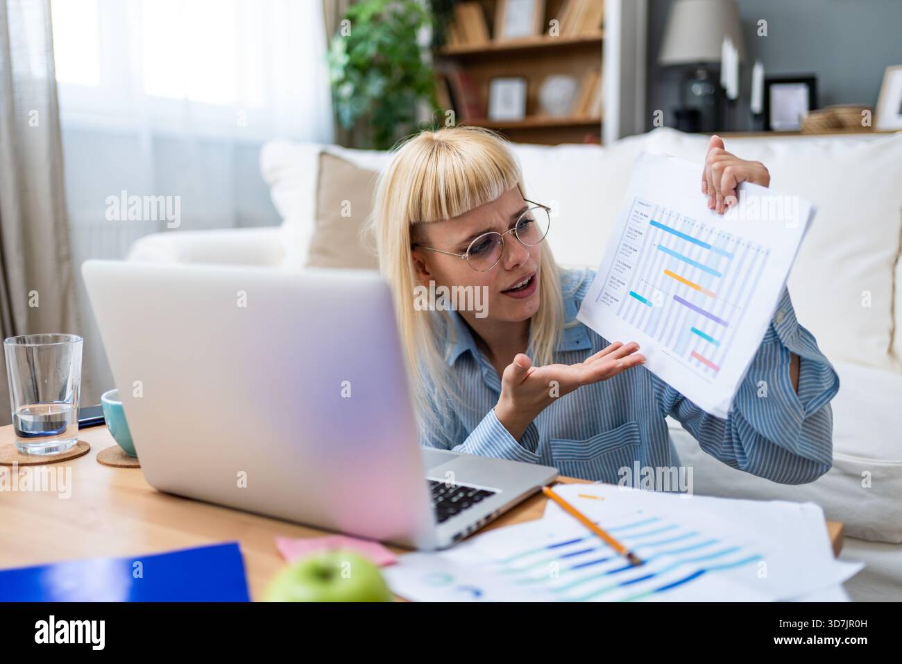 Young professional woman on video call from home holds printed chart ...