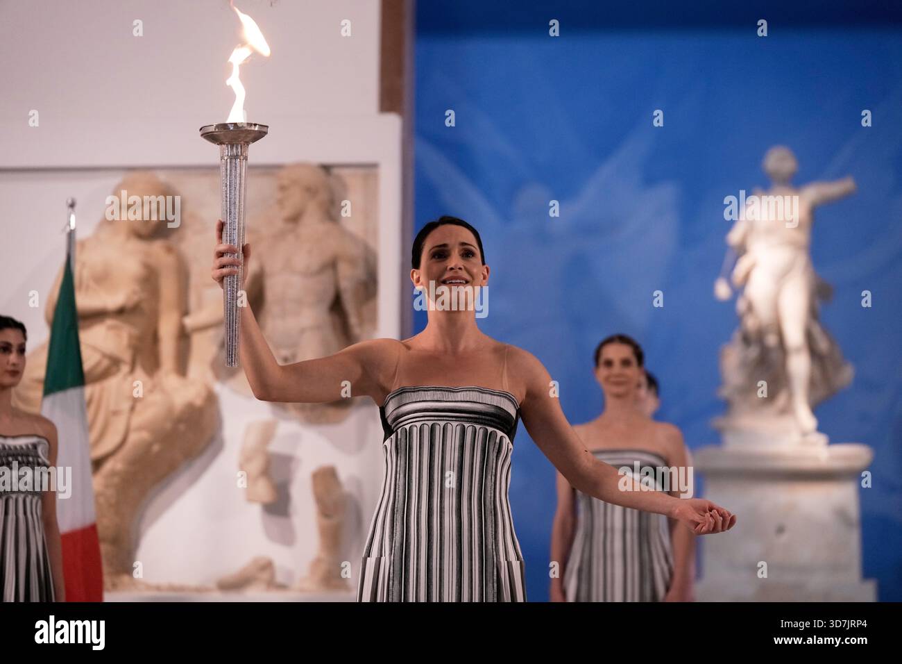 High Priestess Mary Mina, left, holds a torch with the Olympic flame ...