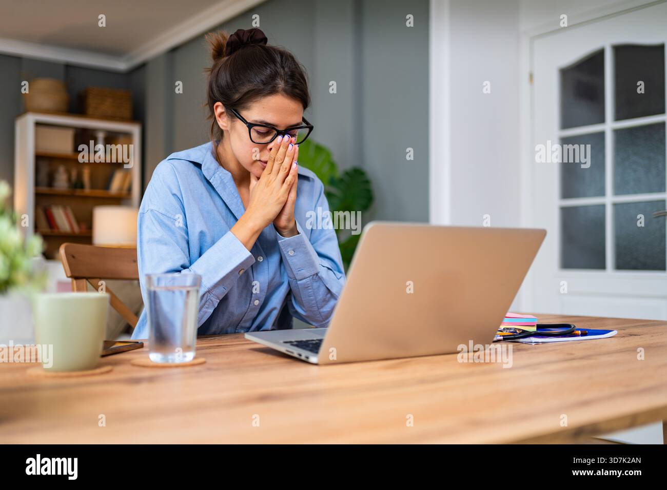 Focused female professional in glasses working on a laptop PC, chin ...
