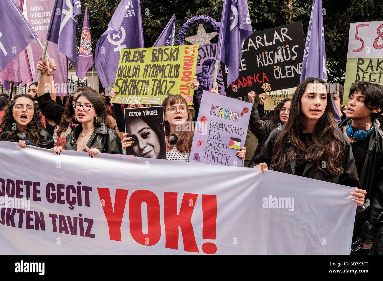 Female protesters chant slogans while holding placards and a banner ...