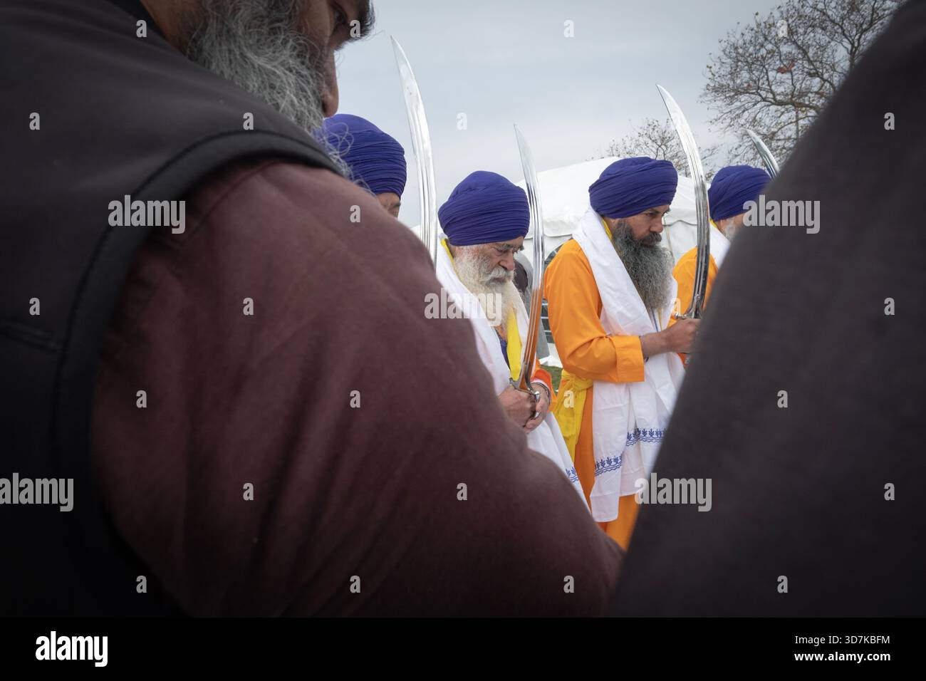 Sikh men in turbans, orange robes & carrying long swords enter the tent ...