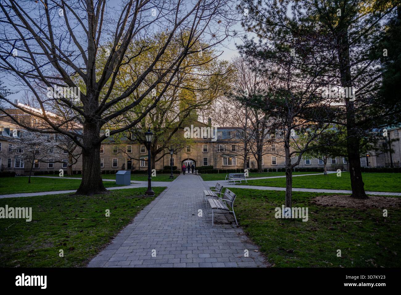 People walking toward a historic campus building across a tree-lined ...