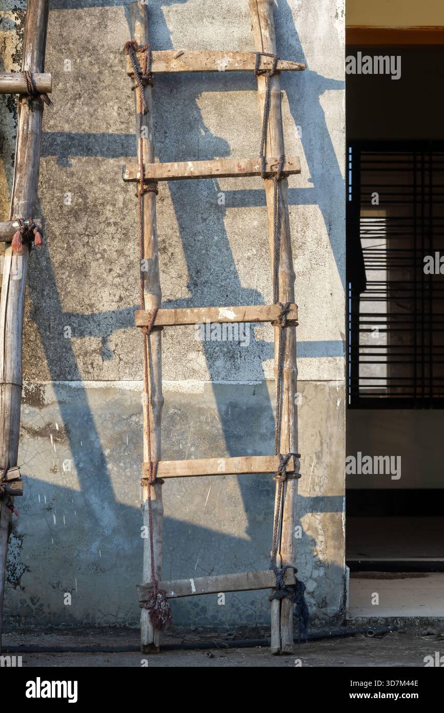 An old, worn handmade ladder crafted from rough-hewn bamboo and natural ...