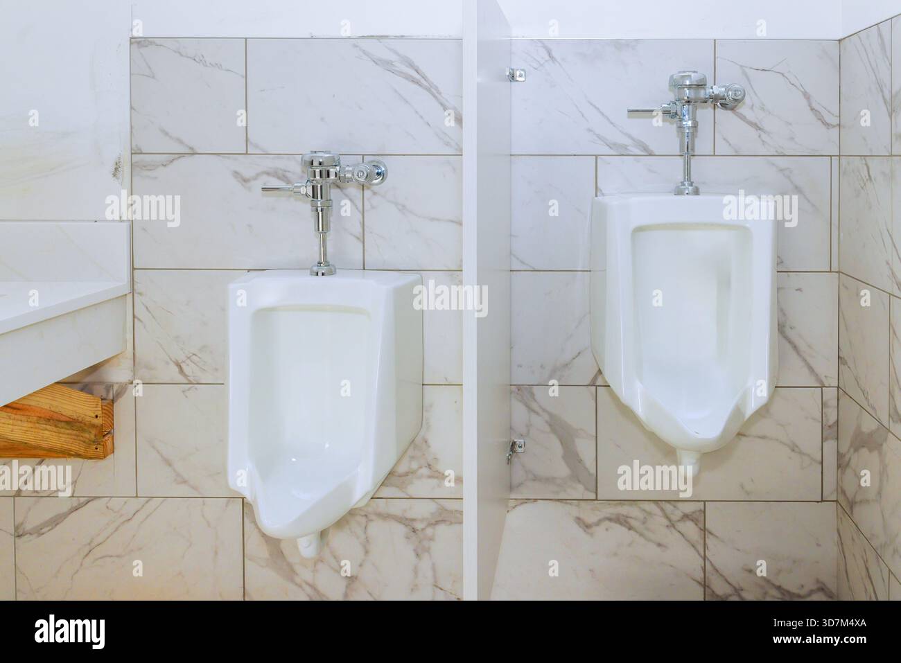 Two modern urinals are placed side by side in tiled restroom with ...