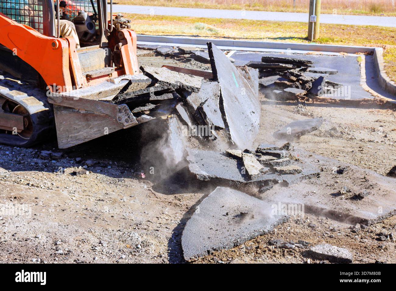 Construction skid steer machinery is breaking up asphalt in parking lot ...