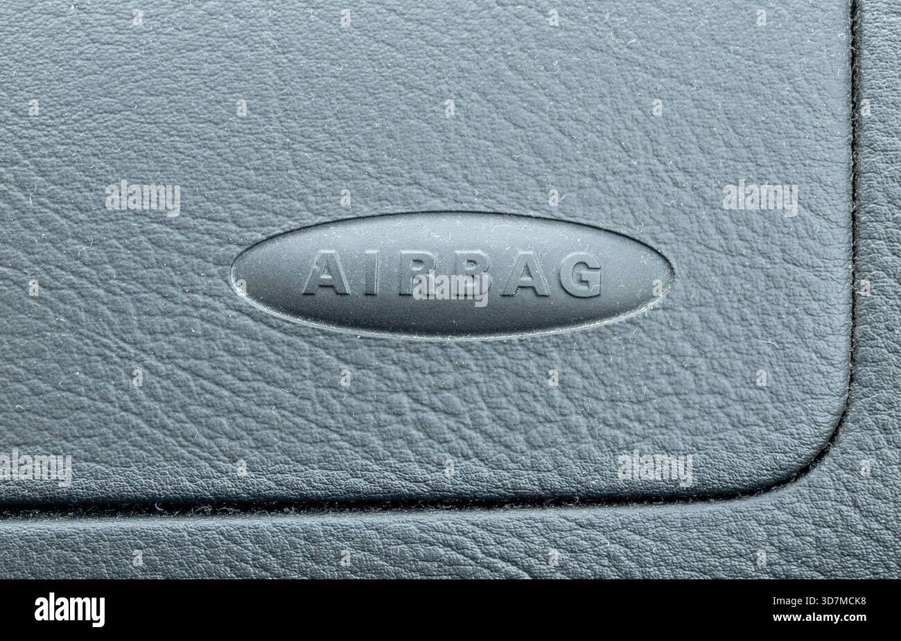 Passenger airbag label on a car dashboard panel, embossed oval symbol ...