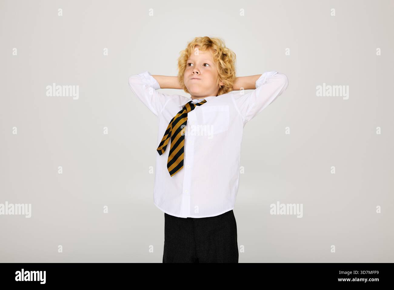 A blonde boy with wavy hair relaxes in his school uniform, puffing ...