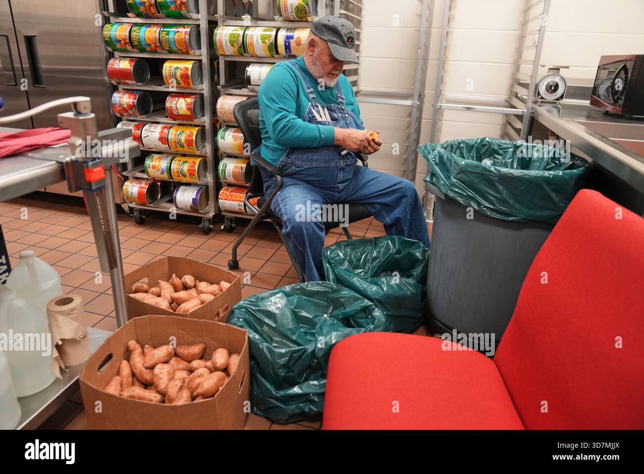 Larry Mease works to peel 240 pounds of sweet potatoes as he helps his ...