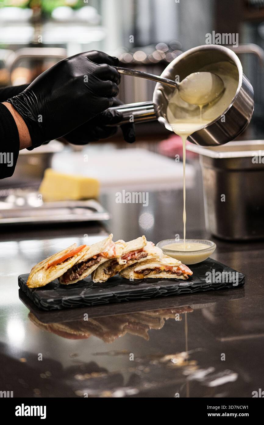 Gloved chef pouring molten cheese over crostini — saucier finishing ...