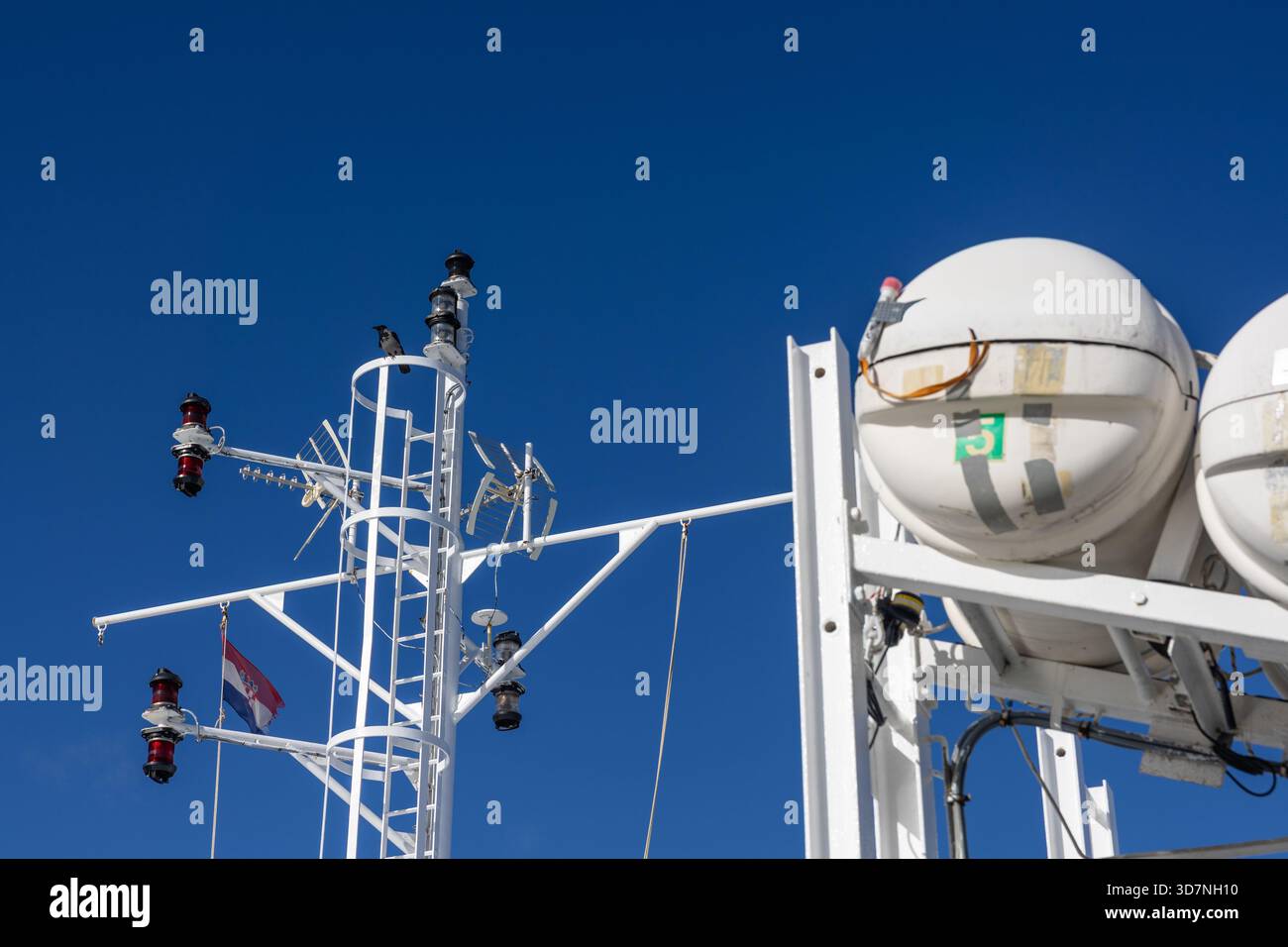 A close view of a white ship mast with navigation lights and rigging ...