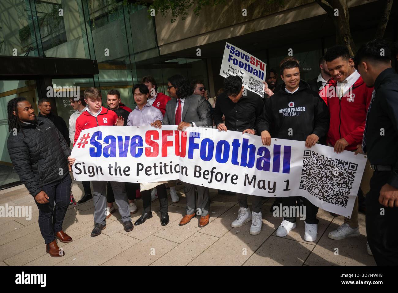 Simon Fraser University football team players hold a banner after ...