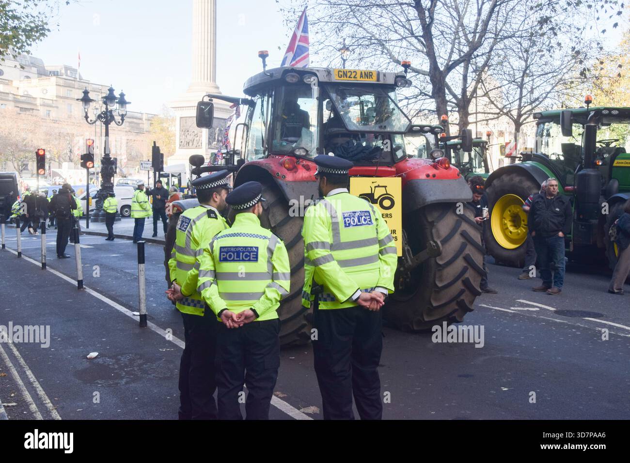 Police officers stand next to tractors blocking a street next to ...