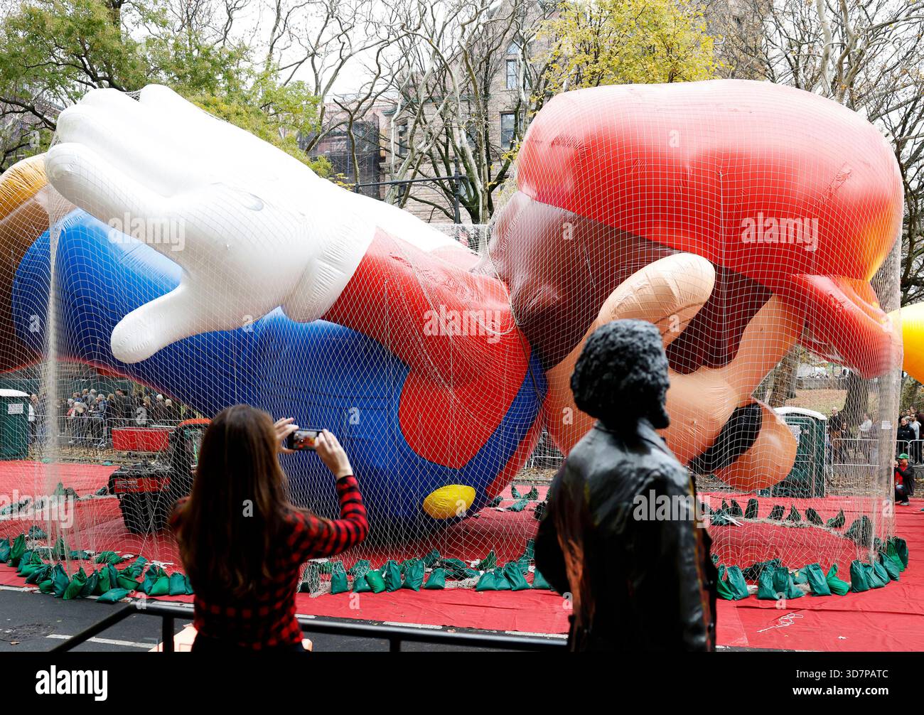 People walk and gather near the Mario Balloon that is held under a net ...