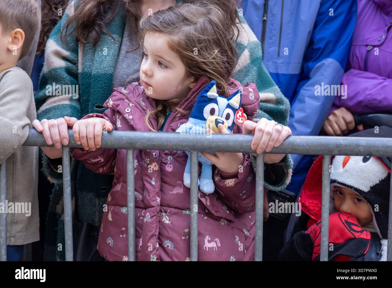 A young girl holds a Bluey stuffed animal while watching the Bluey ...