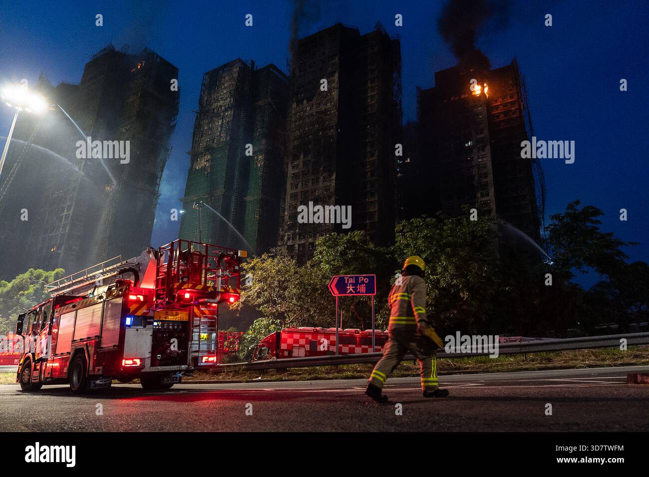 A firefighter walks past the fire scene at Wang Fuk Court, a ...