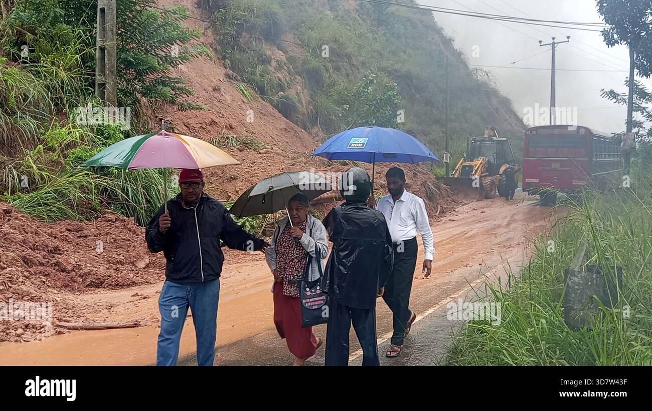 People walk past a section of a highway blocked by a landslide caused by heavy rain in Badulla ...