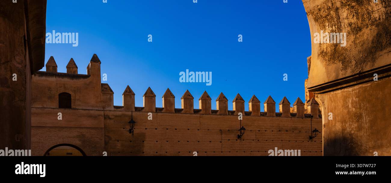 Ancient fortress walls with pointed towers under a clear blue sky. Fez ...